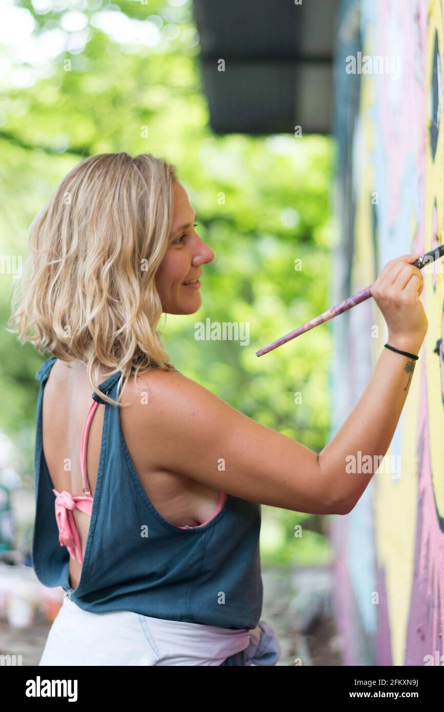 Side view of female artist painting wall Stock Photo - Alamy