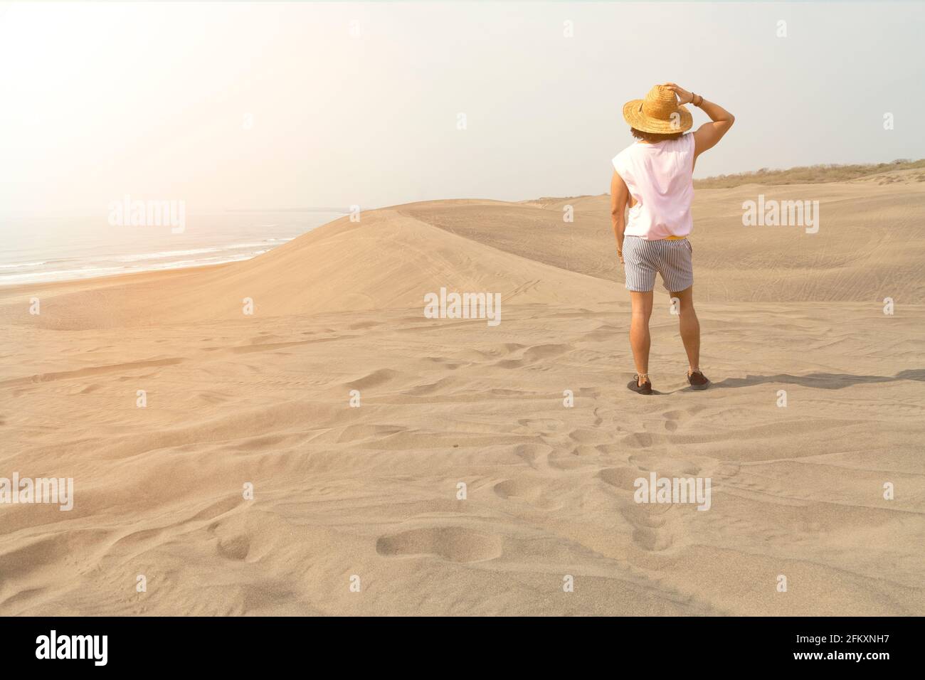 Young male holding his hat, on sand dunes, during golden hour Stock ...