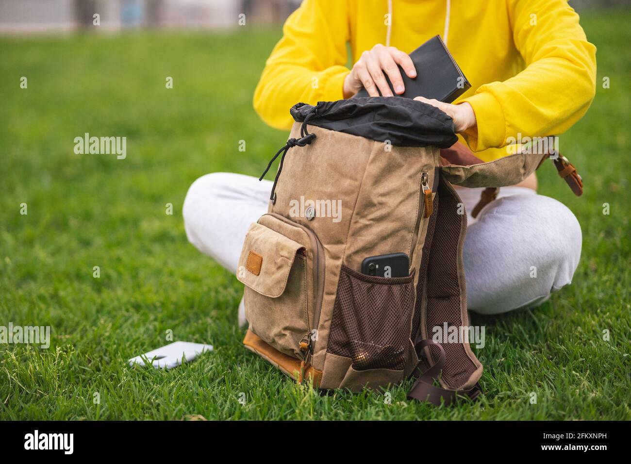 Spanish student preparing the backpack on the grass to go to class ...