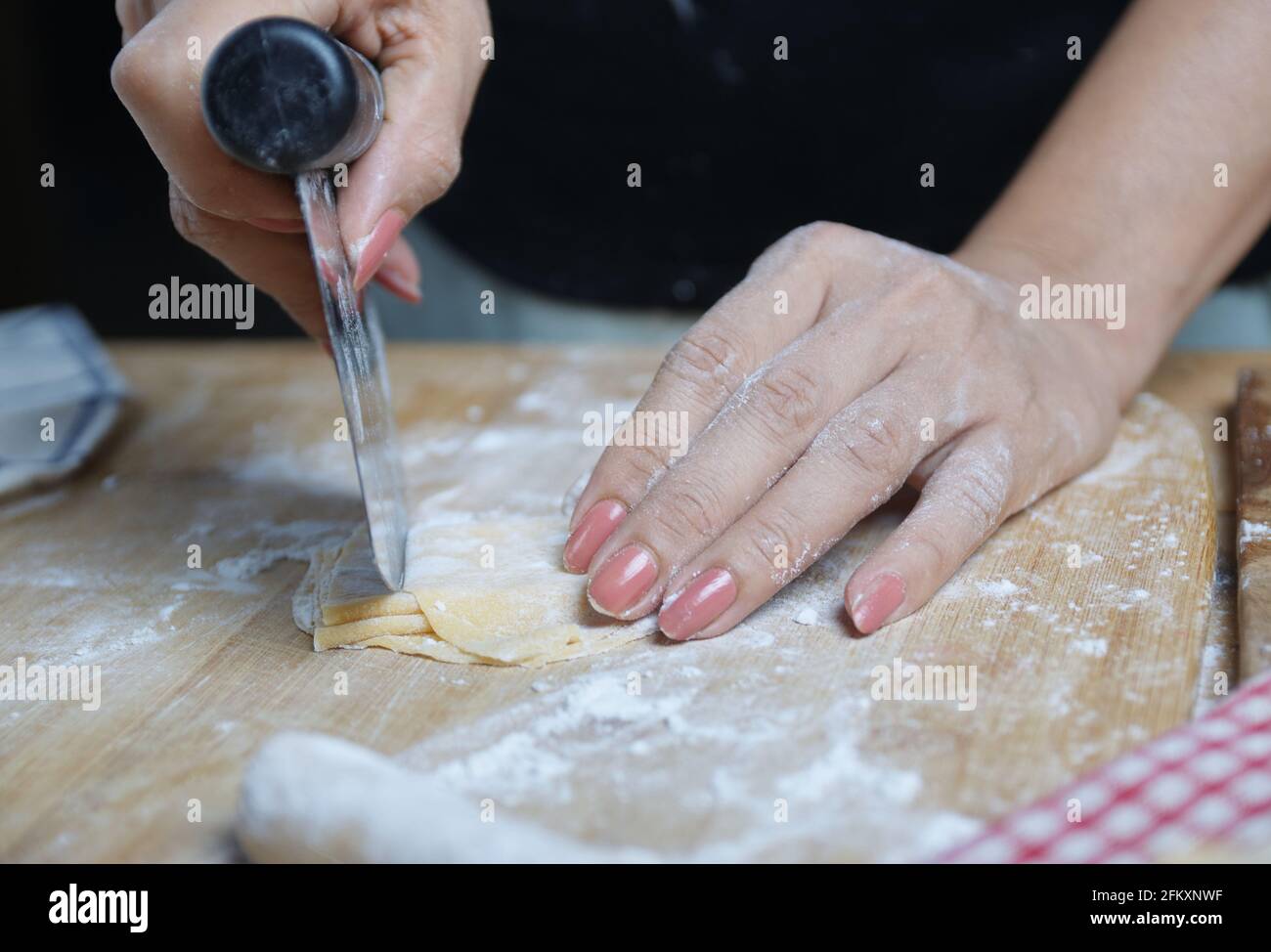 Close-up view a woman cutting the dough of homemade pasta Stock Photo ...