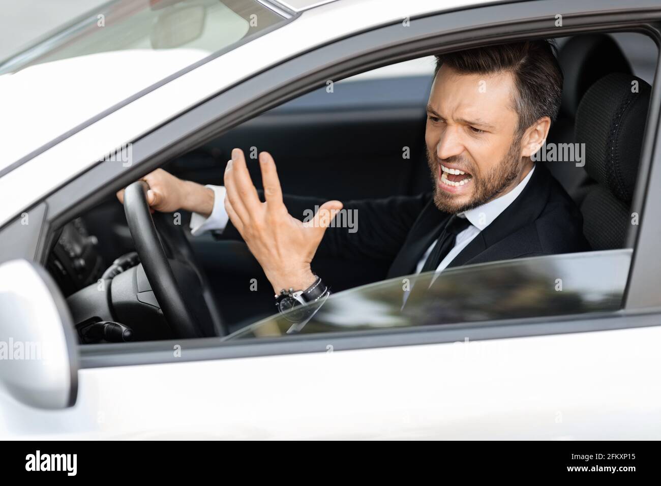 Expressive middle-aged businessman screaming while driving car Stock ...