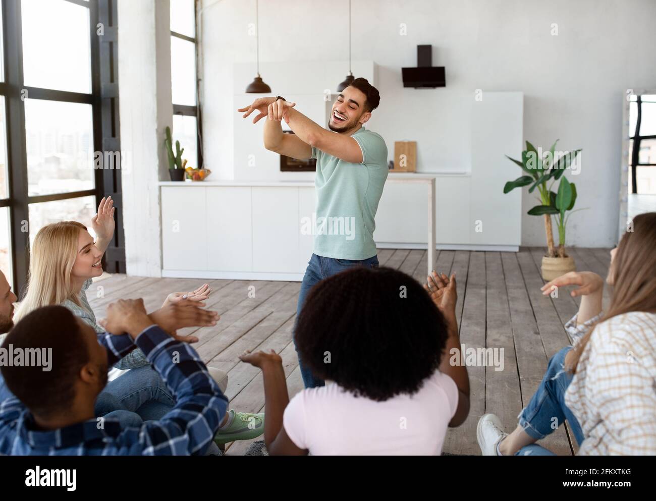 Group of happy multiracial friends playing charades guessing game at ...
