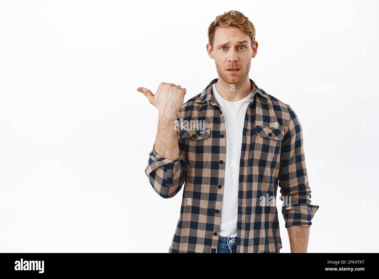 Confused redhead adult man pointing finger aside at something strange ...