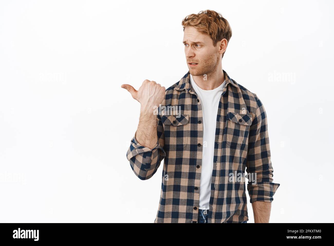 Skeptical redhead man cringe from something bad, looking and pointing ...