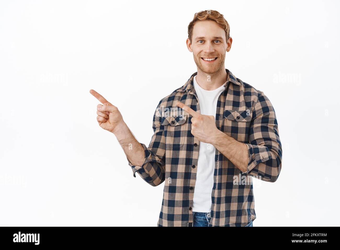 This way. Smiling redhead male model pointing fingers left and showing ...