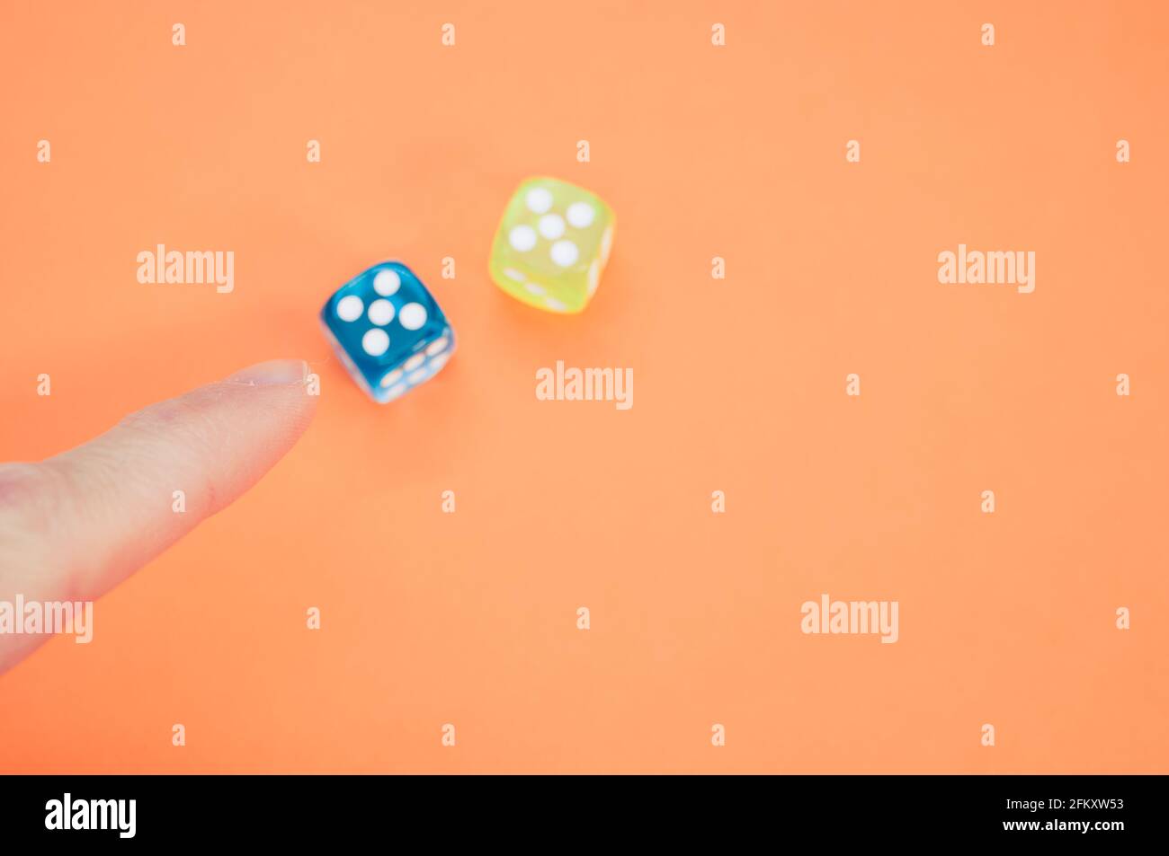 Closeup shot of a finger pointing at colored dice cubes on a colorful ...