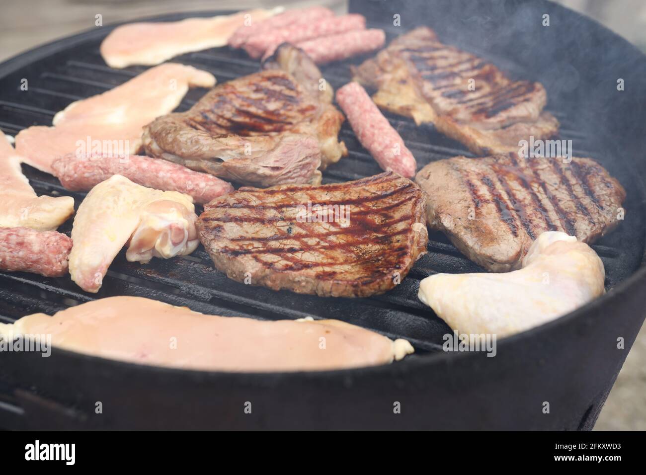 Process of making barbecue with meat fillets on a grill Stock Photo - Alamy