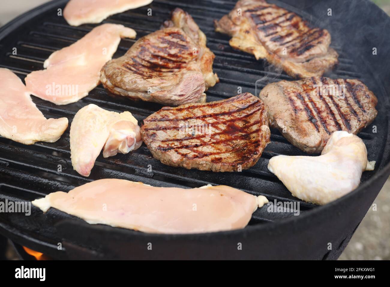 Process of making barbecue with meat fillets on a grill Stock Photo - Alamy