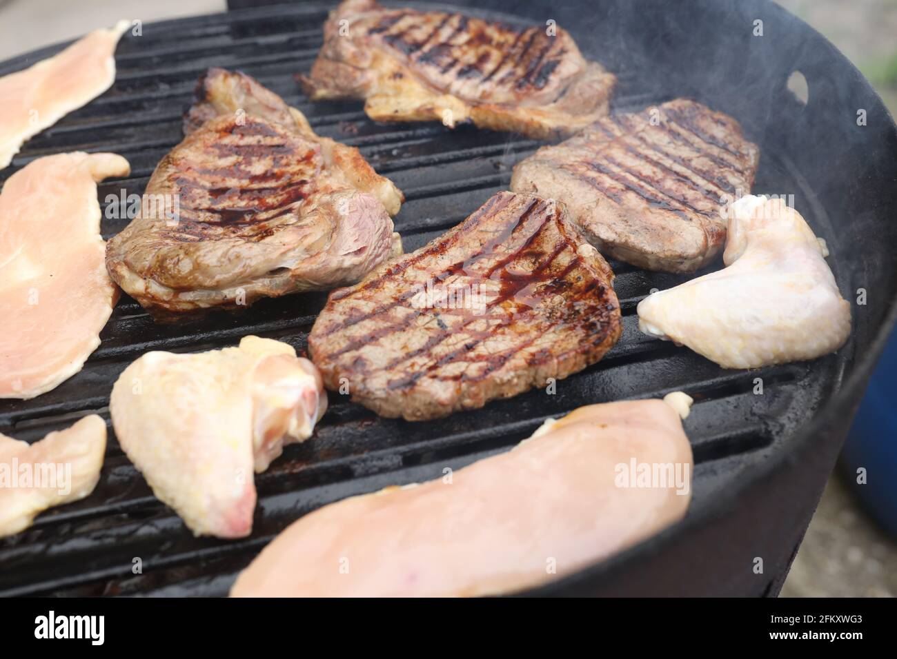 Process of making barbecue with meat fillets on a grill Stock Photo - Alamy