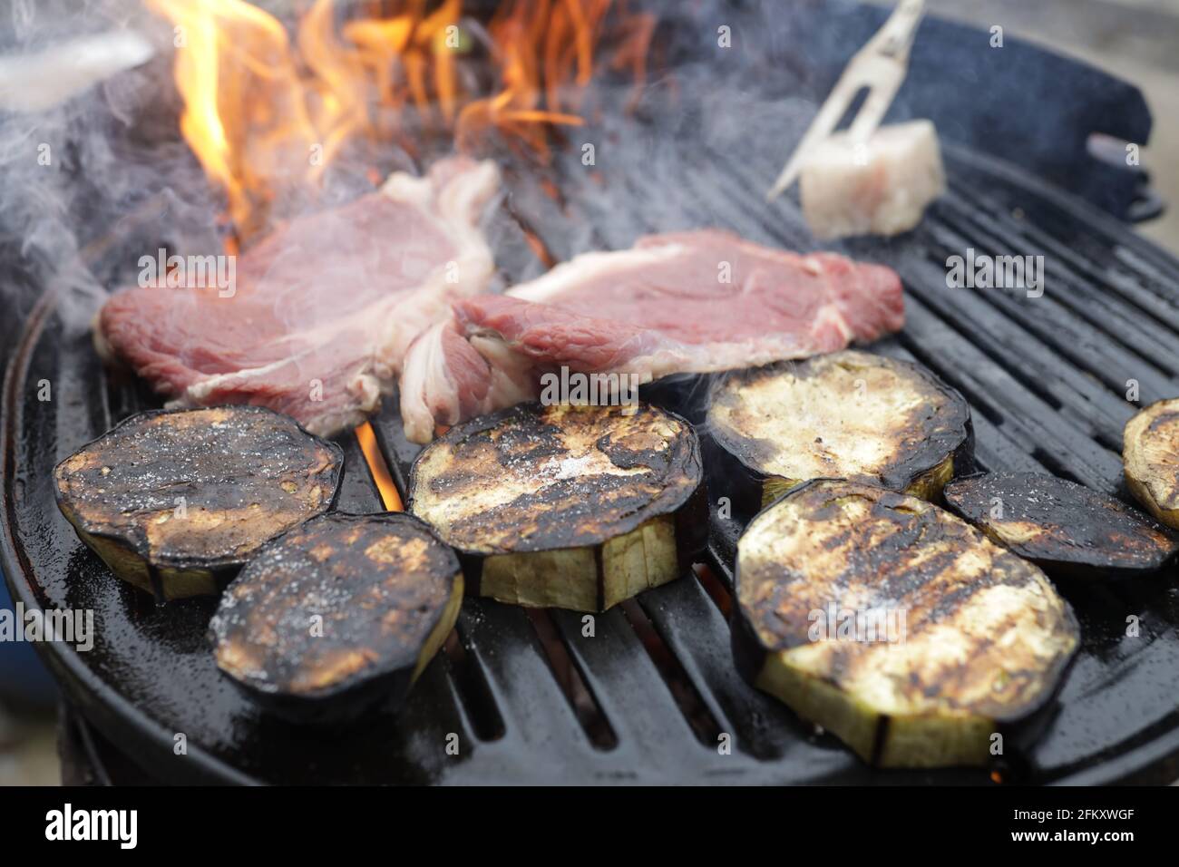 Process of making barbecue with meat fillets and vegetables on a grill ...