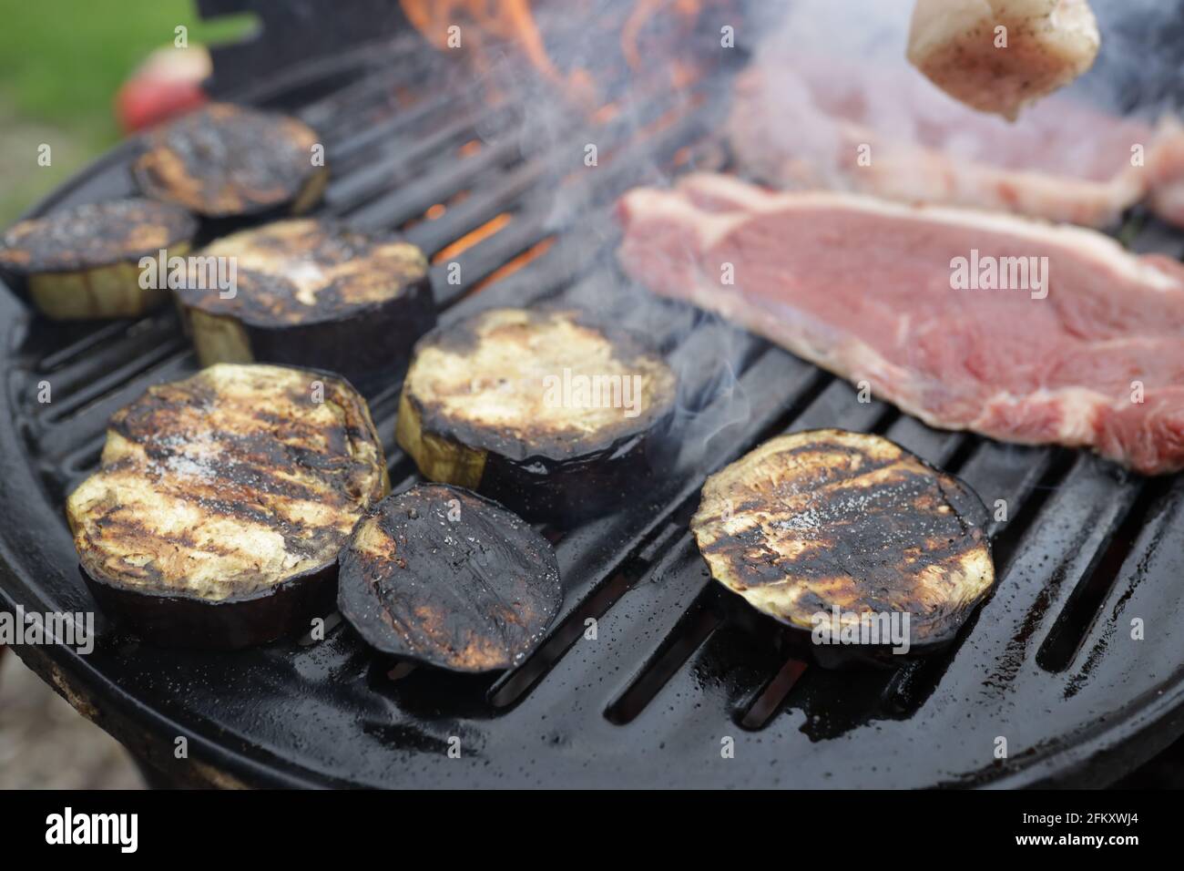 Process of making barbecue with meat fillets and vegetables on a grill ...