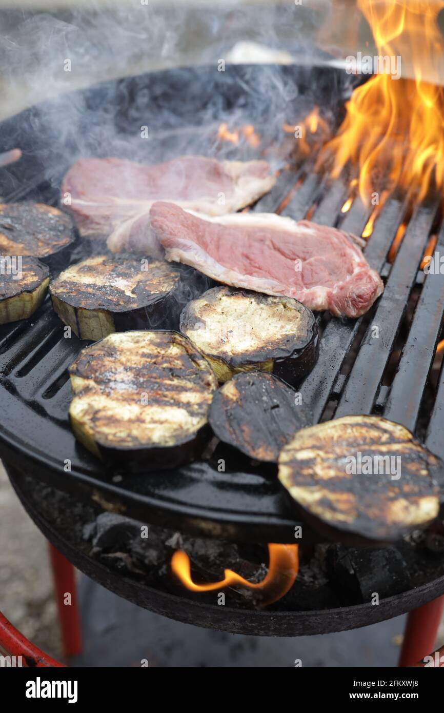 Process of making barbecue with meat fillets and vegetables on a grill ...