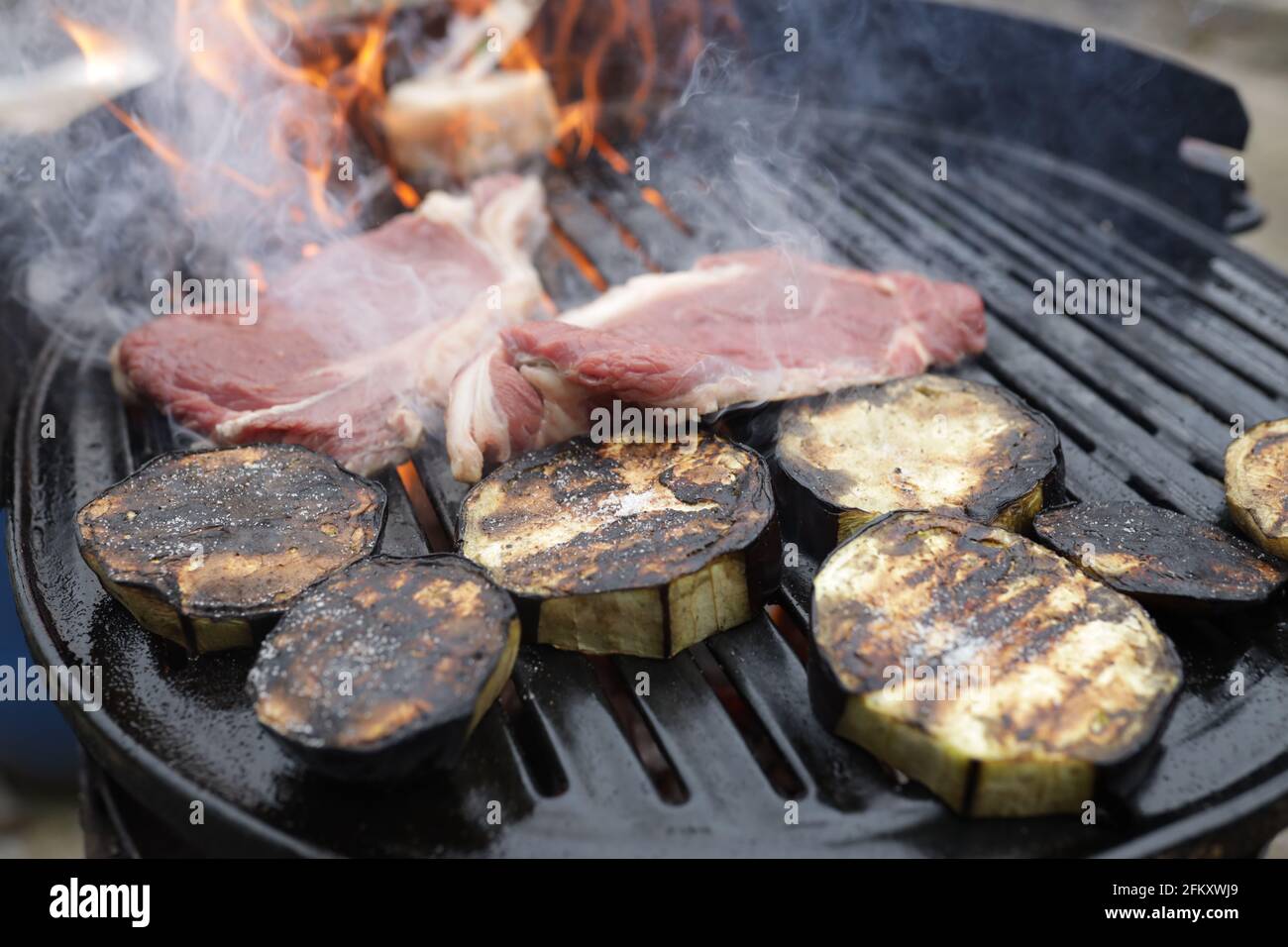 Process of making barbecue with meat fillets and vegetables on a grill ...