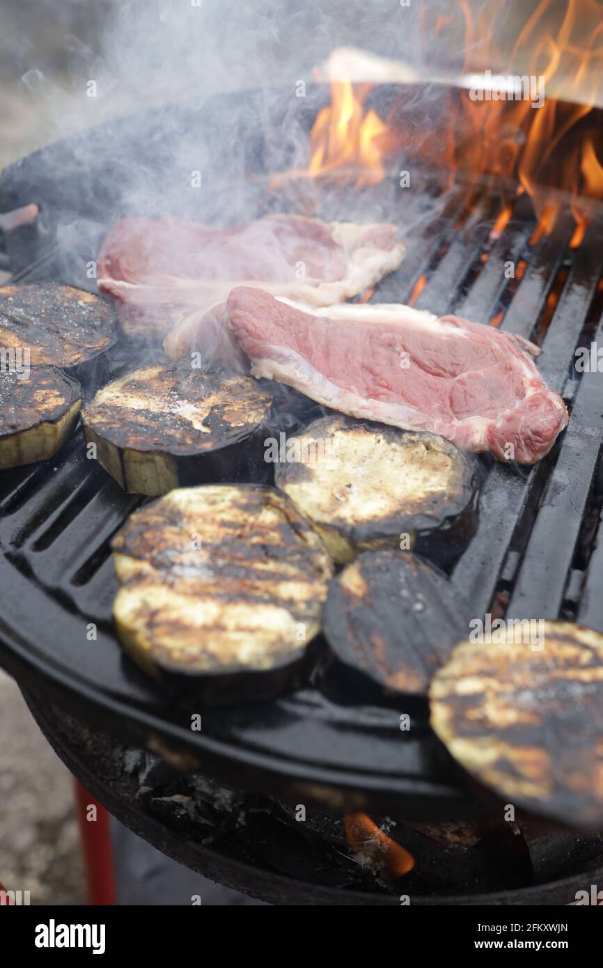 Process of making barbecue with meat fillets and vegetables on a grill ...