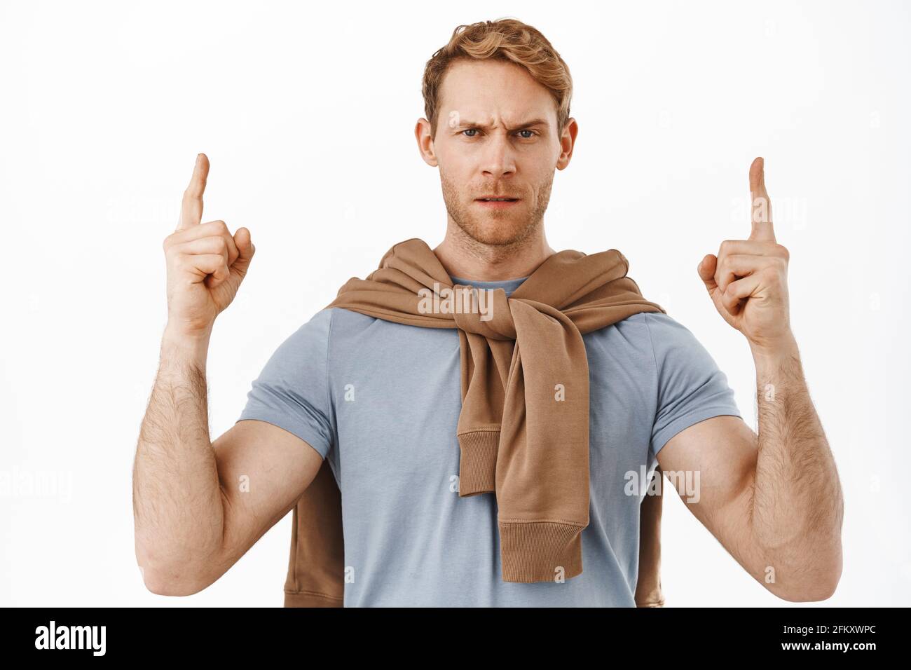Angry redhead man pointing fingers up, frowning and looking ...