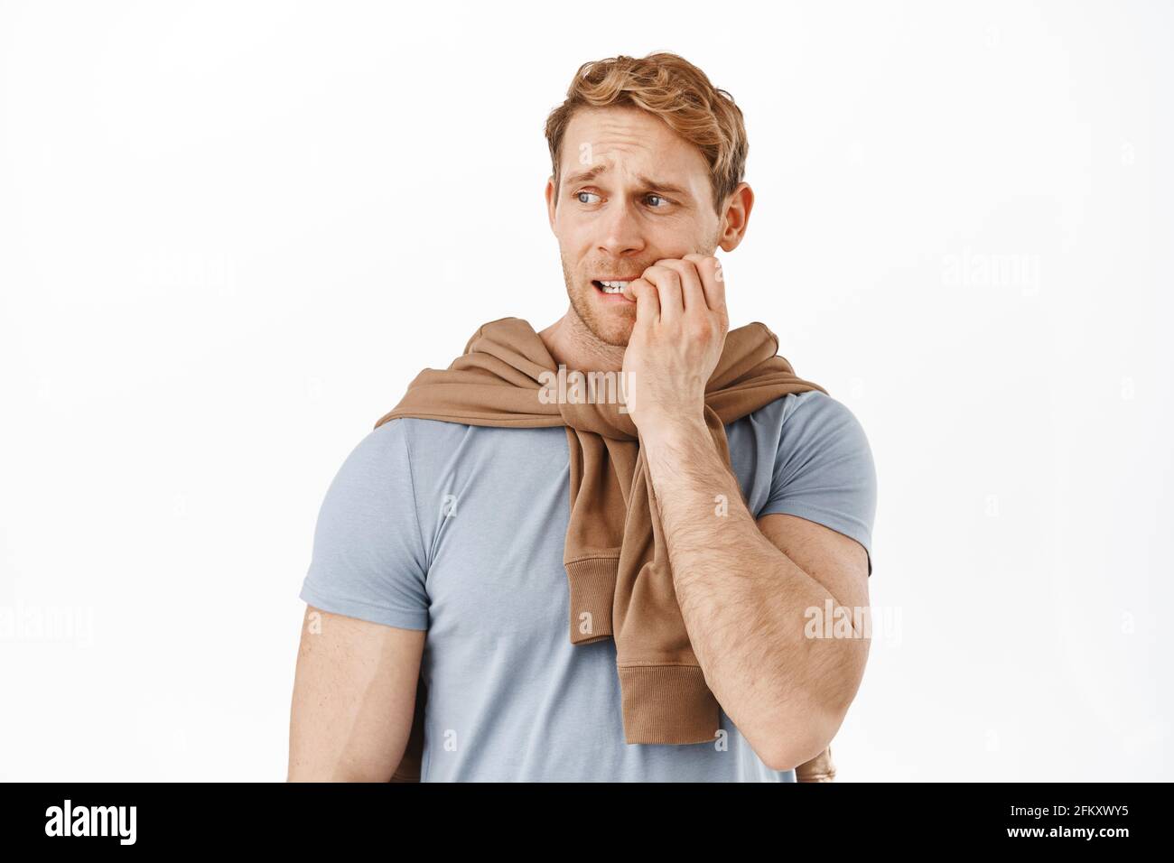 Image of anxious red head man biting finger nails and looking left with ...