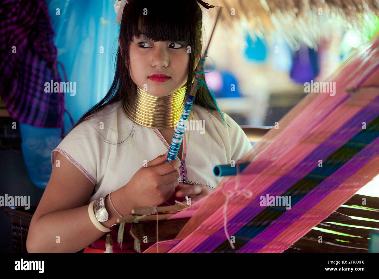 A young Karen long neck tribe girl weaves silk on her loom in a Karen ...