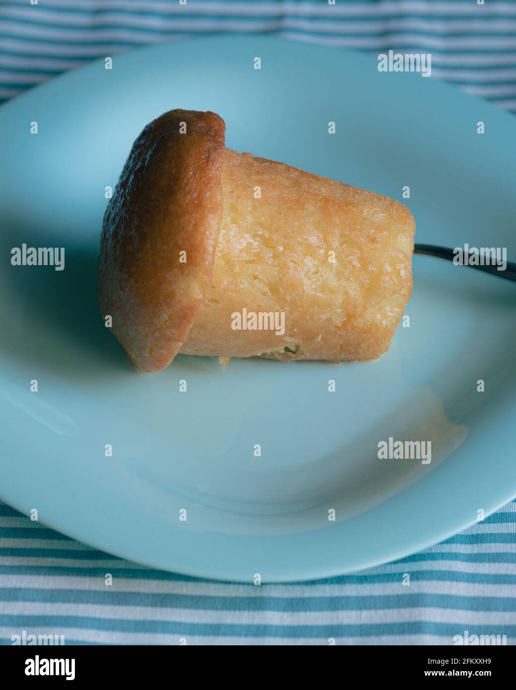 Neapolitan baba with rum on a blue plate for a sweet and tasteful snack ...