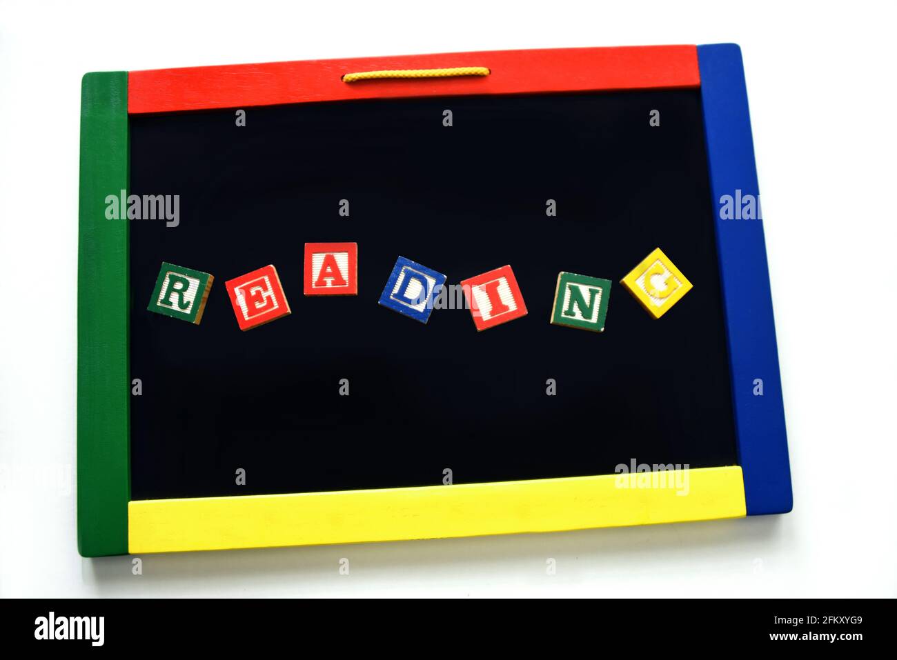 Magnetic block letters spell the word reading. They cling to a magnetic ...