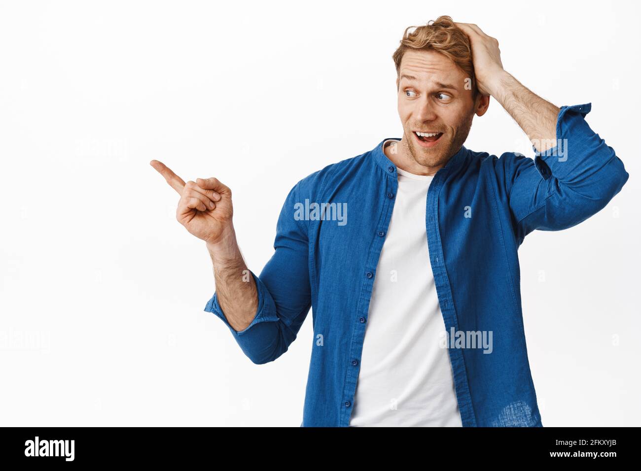 Surprised redhead man touch head, pointing and looking left at ...