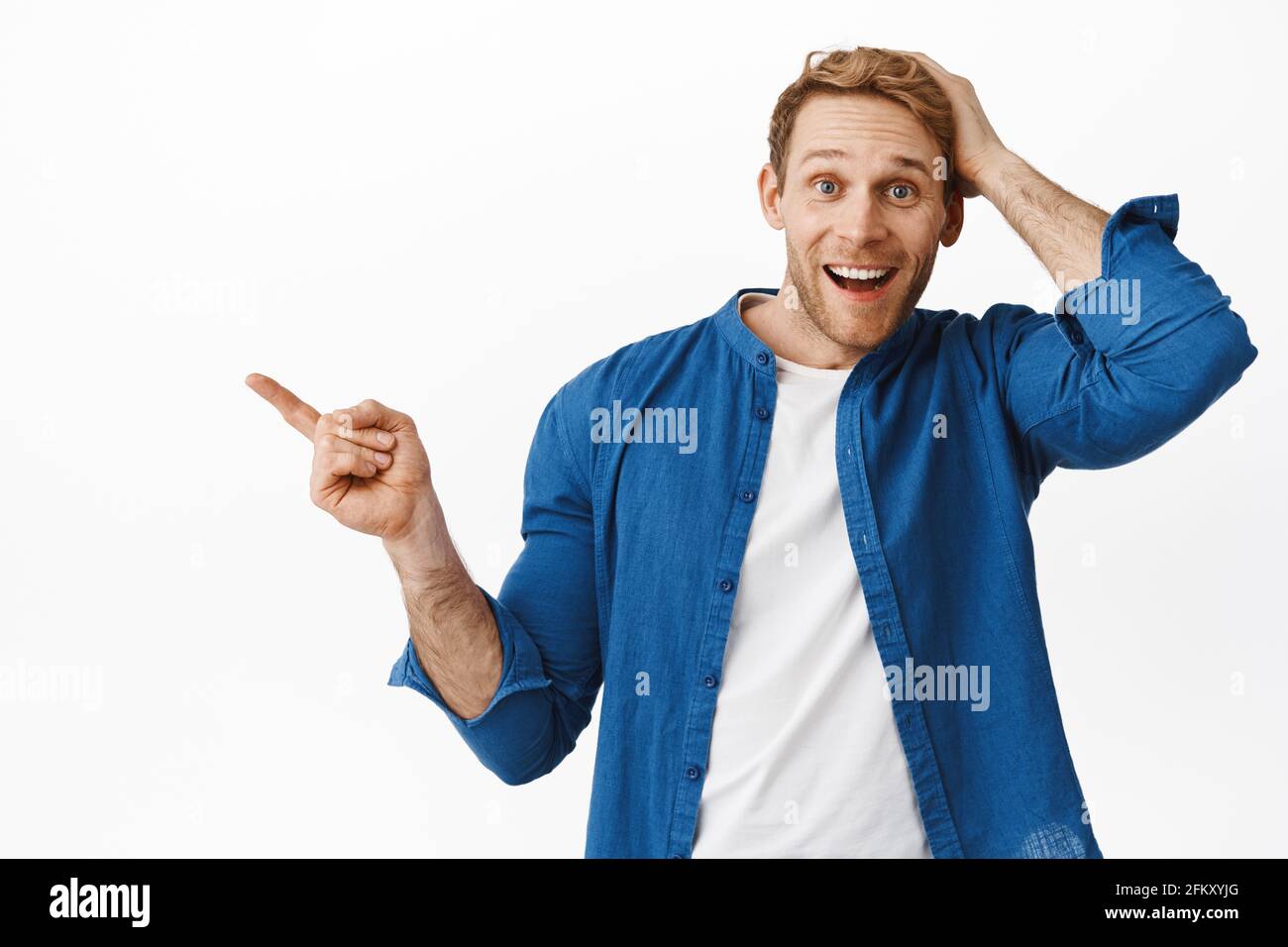 Happy surprised man smiling, pointing finger left and touching head ...