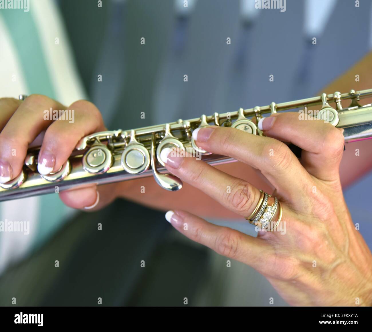 Senior woman practices her flute. Closeup shows her fingers in position ...