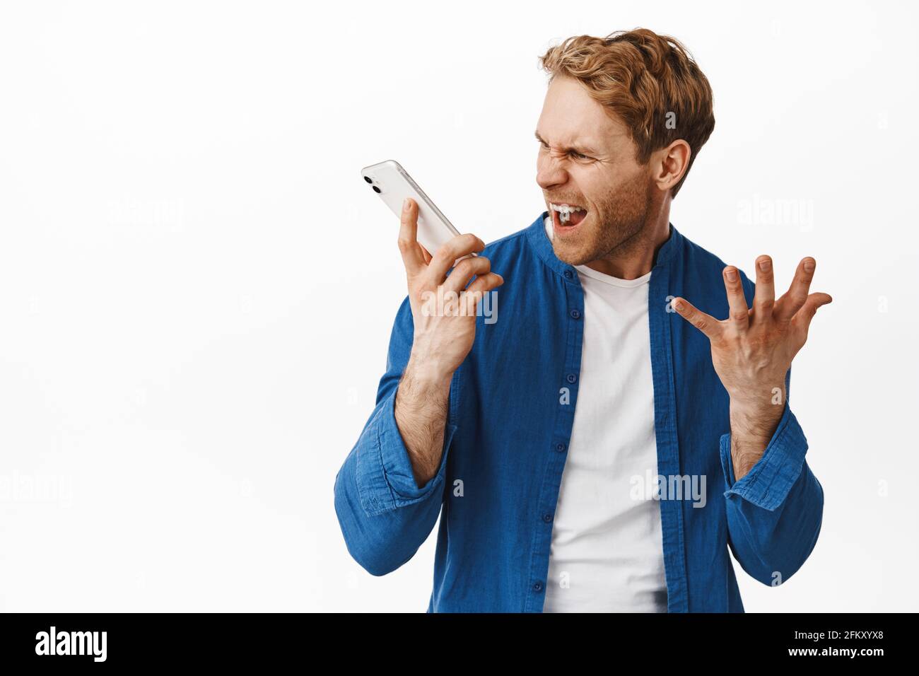 Portrait of angry pissed off redhead man shouting at smartphone ...