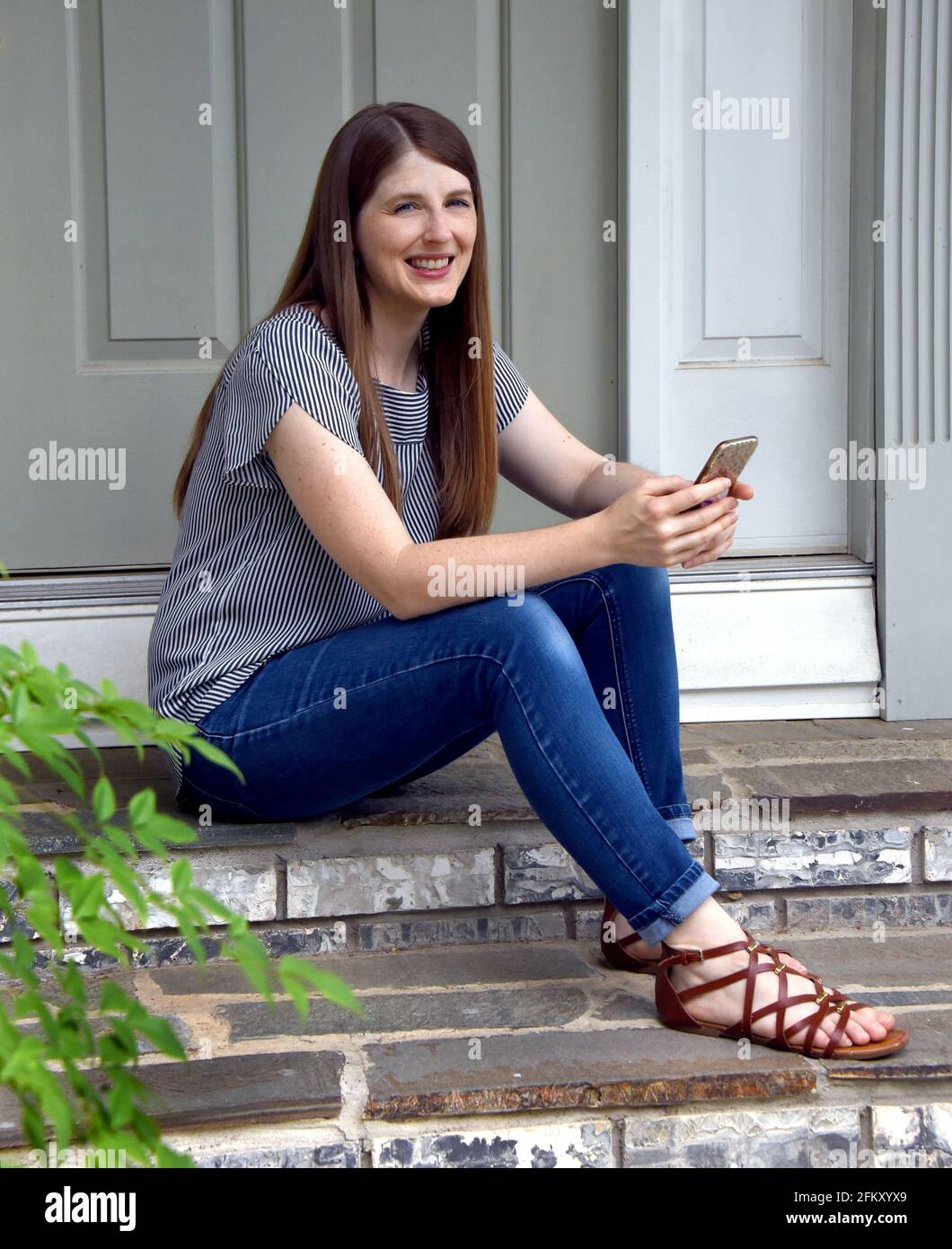 Young woman pause, as she checks her emails, to look up and smile. She ...