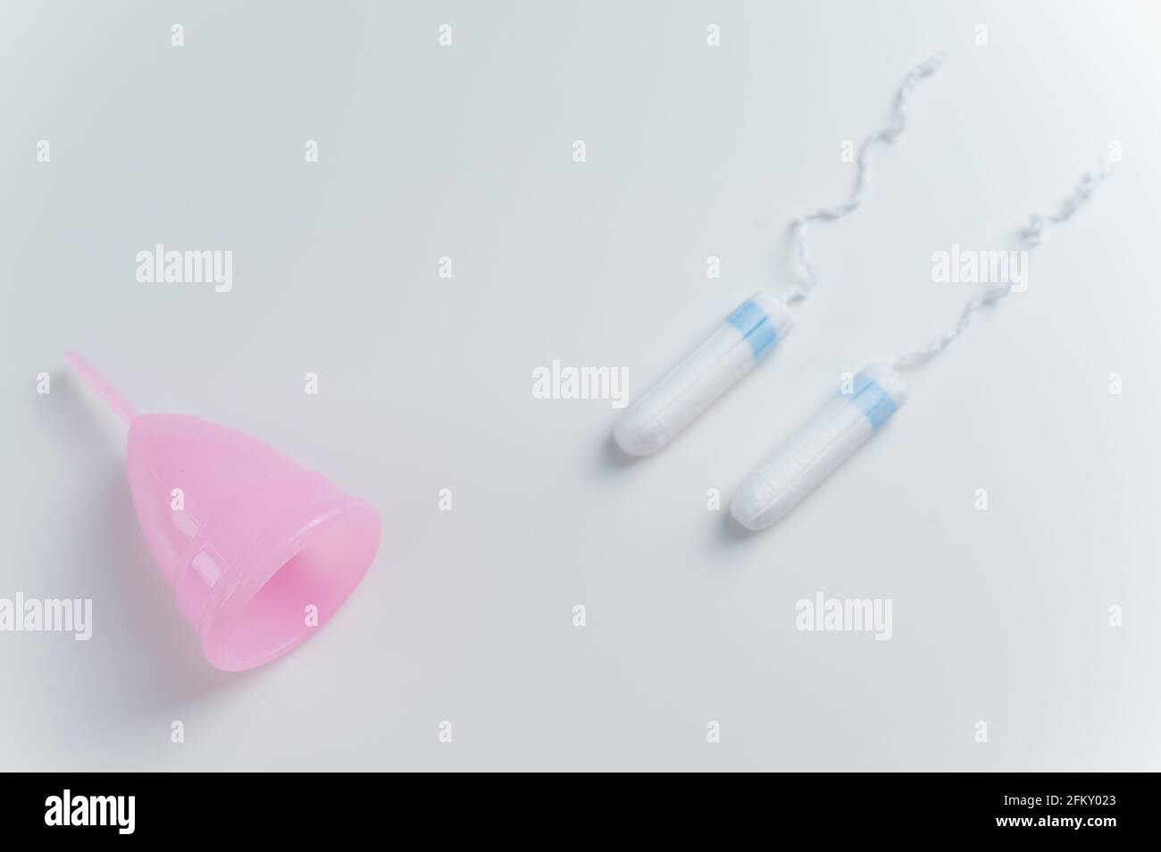 Pink menstrual cup and tampons on a white background. Comparison of ...