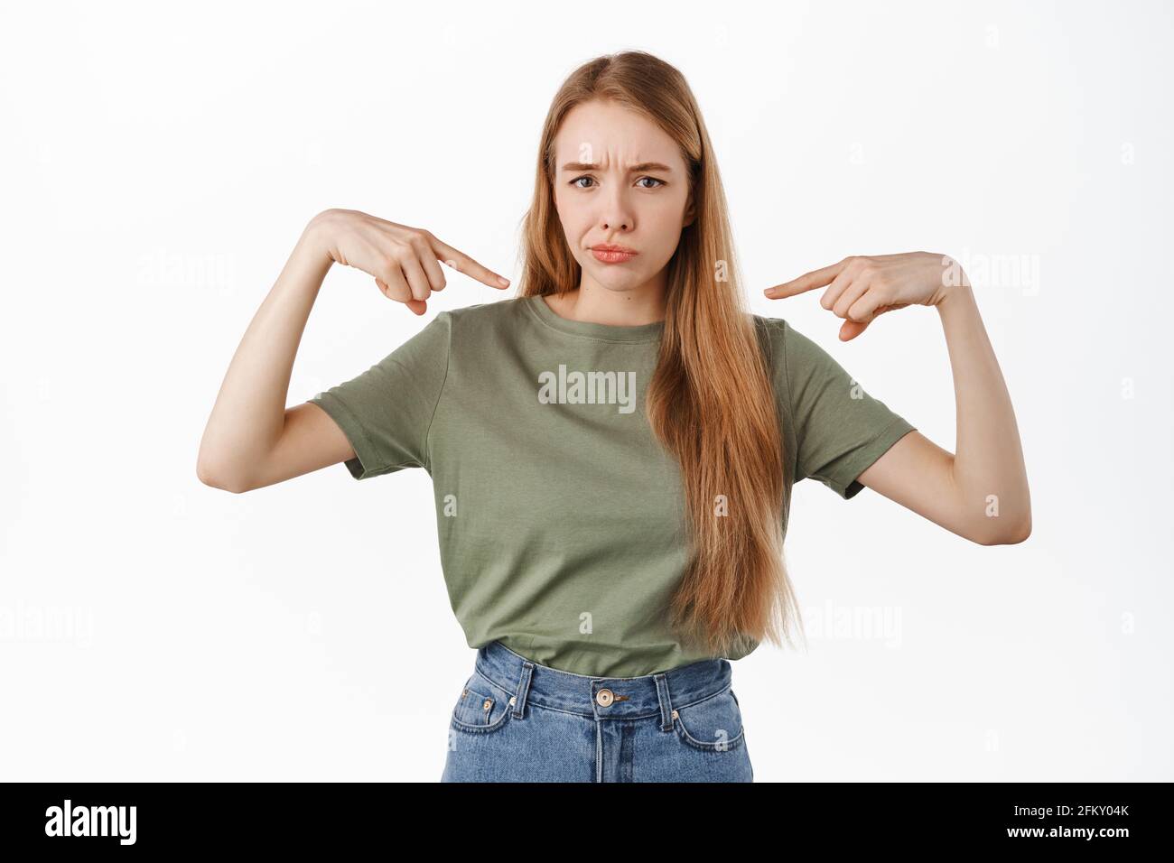 Sad and disappointed young woman pointing at herself, sulking from ...