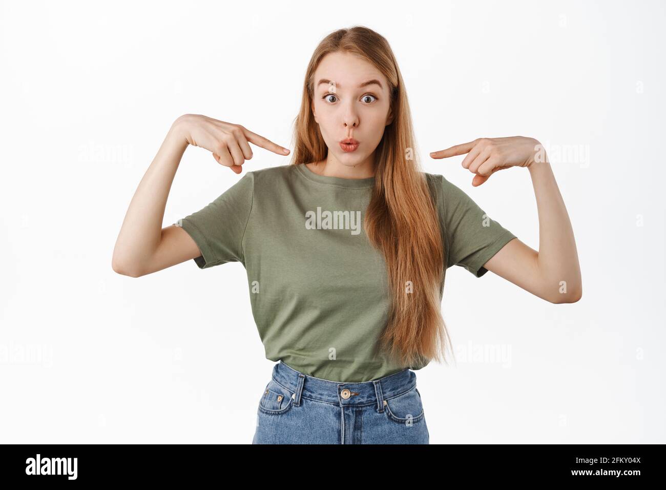 Image of girl looks startled and surprised as pointing at herself ...