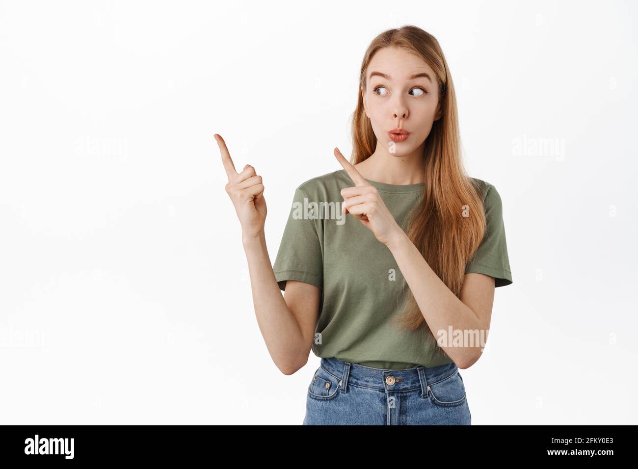 Surprised blond girl peek at product banner, pointing at upper left ...