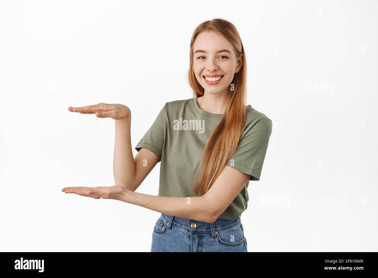 Young smiling female model showing an item, holding something, empty ...