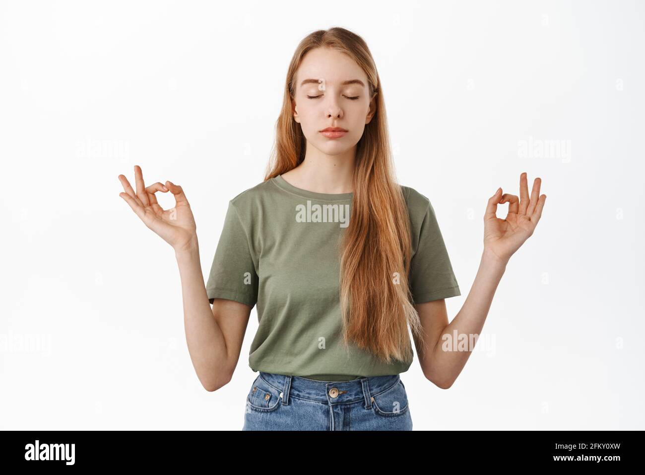 Stay calm. Relaxed young woman meditating, close eyes and hold hands ...