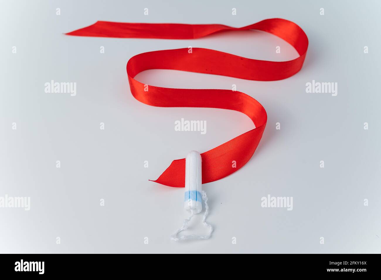 Tampon and red satin ribbon on a white background. Means of intimate ...
