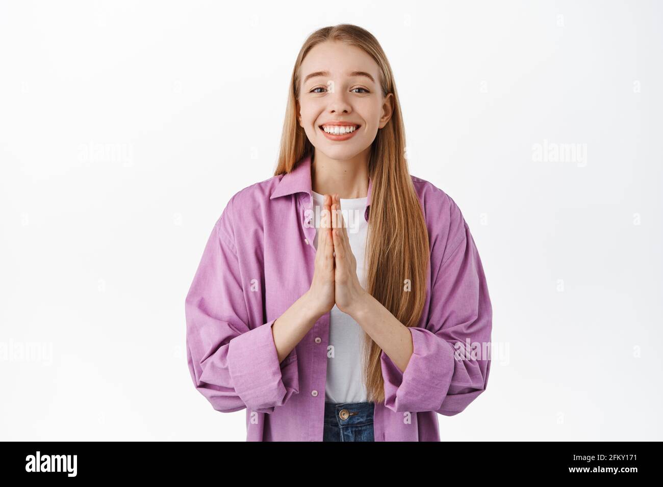 Pretty please. Smiling cute blond girl asking for favour, holding hands ...