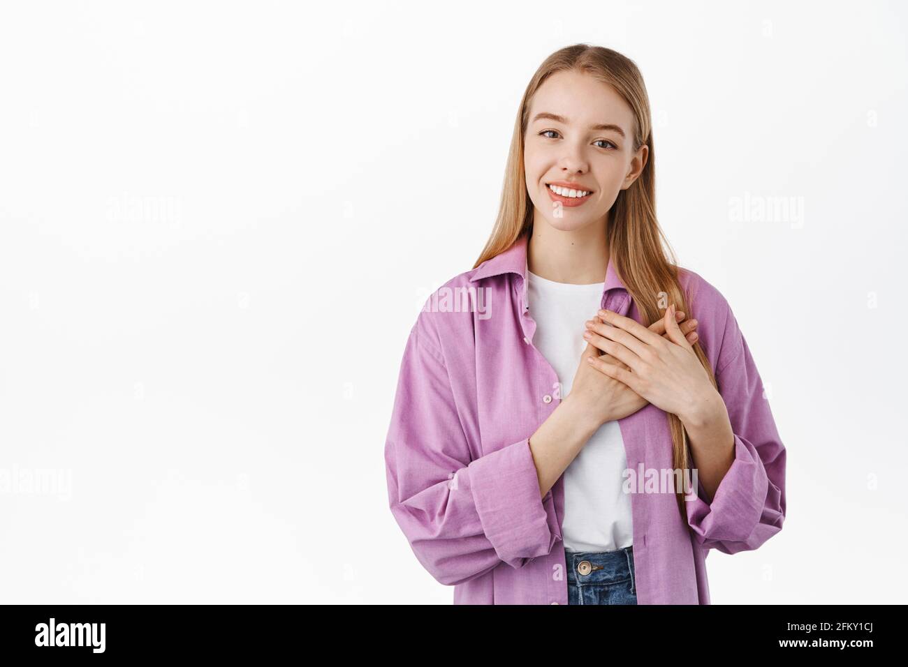 Portrait of beautiful blond girl feeling touched and grateful, looking ...
