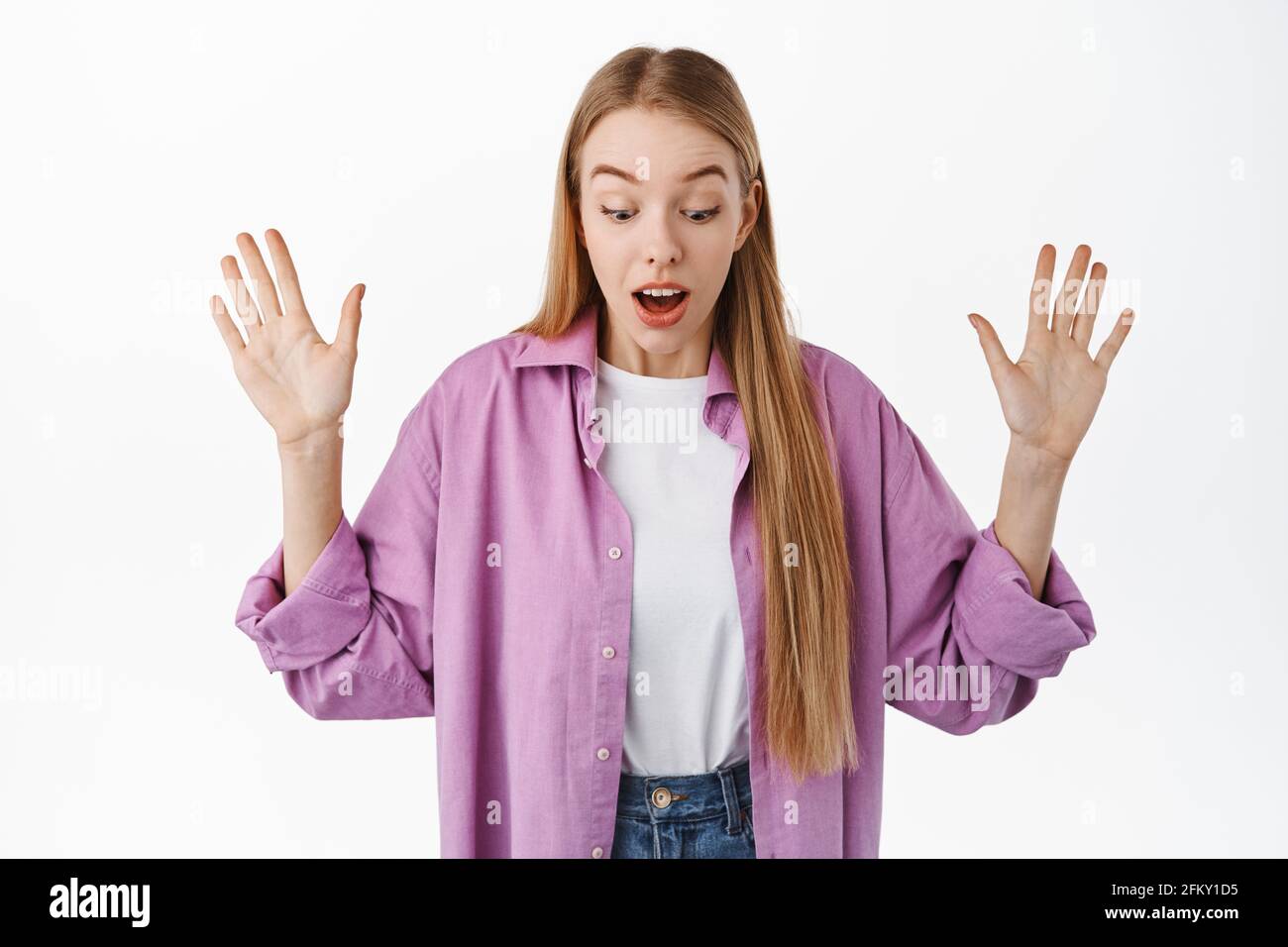 Excited and surprised blond girl looking down with amazed gasp and ...