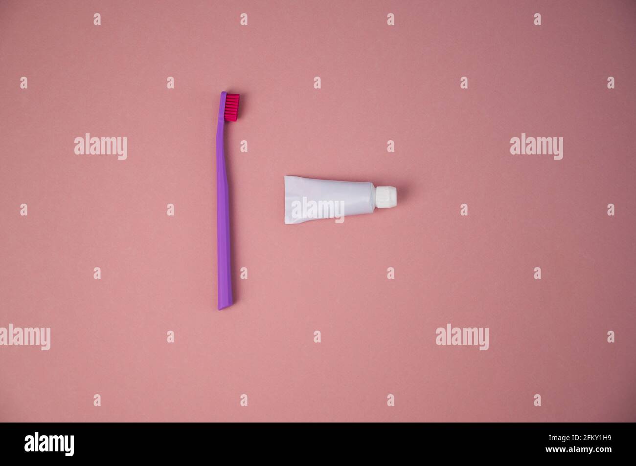 Toothbrush and a tube of toothpaste on a pink background. Oral hygiene ...