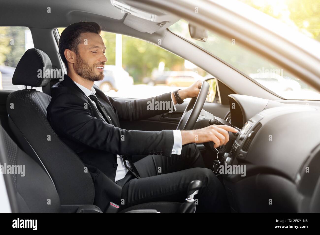 Handsome businessman driving car to airport, turning on music Stock ...