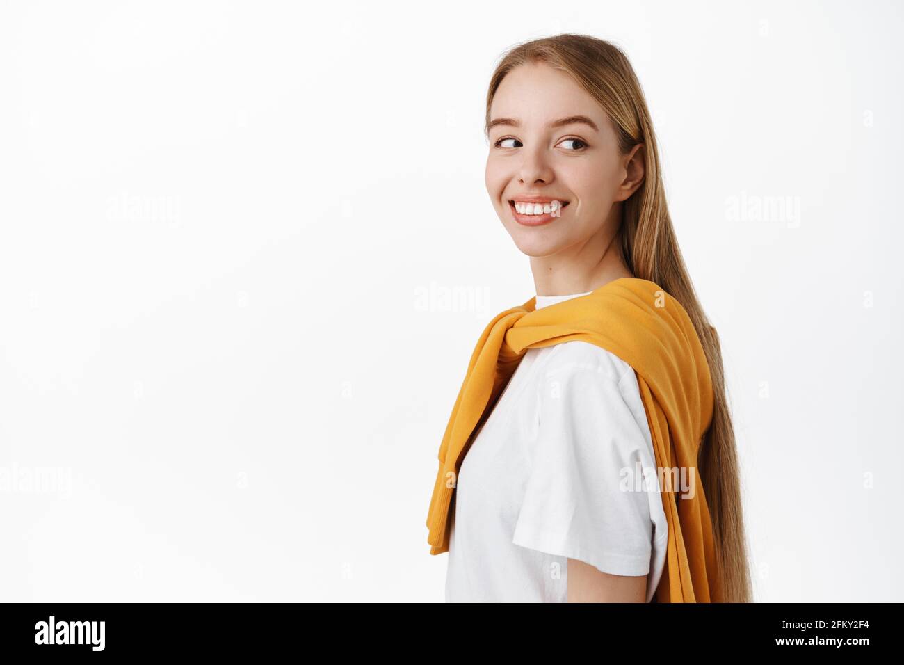 Smiling modern girl turn around, looking behind her shoulder with happy ...
