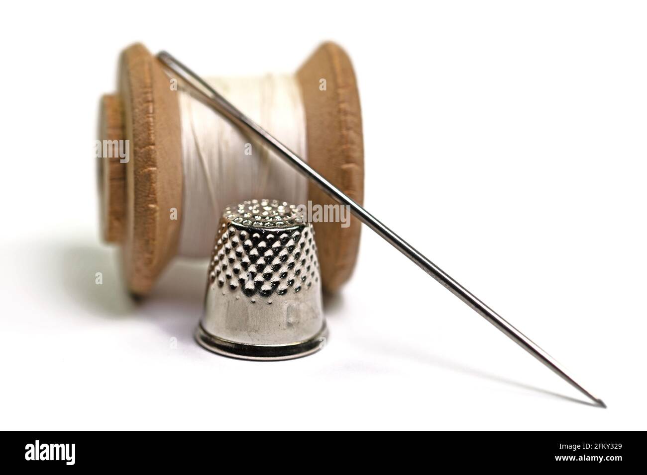 Thimble, sewing needle and thread against white background Stock Photo ...