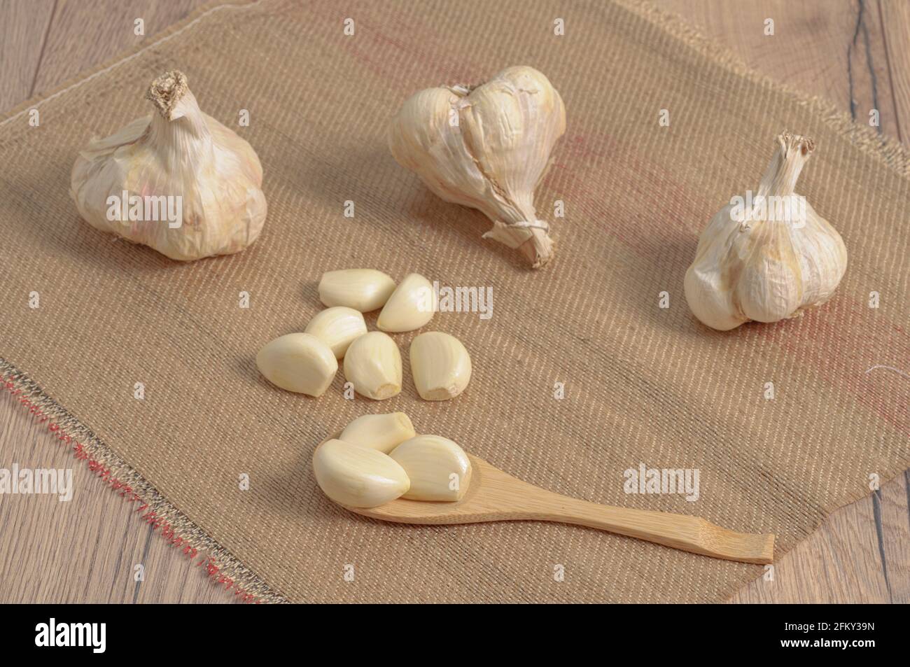 Three heads of garlic and garlic cloves on a wooden board Stock Photo ...