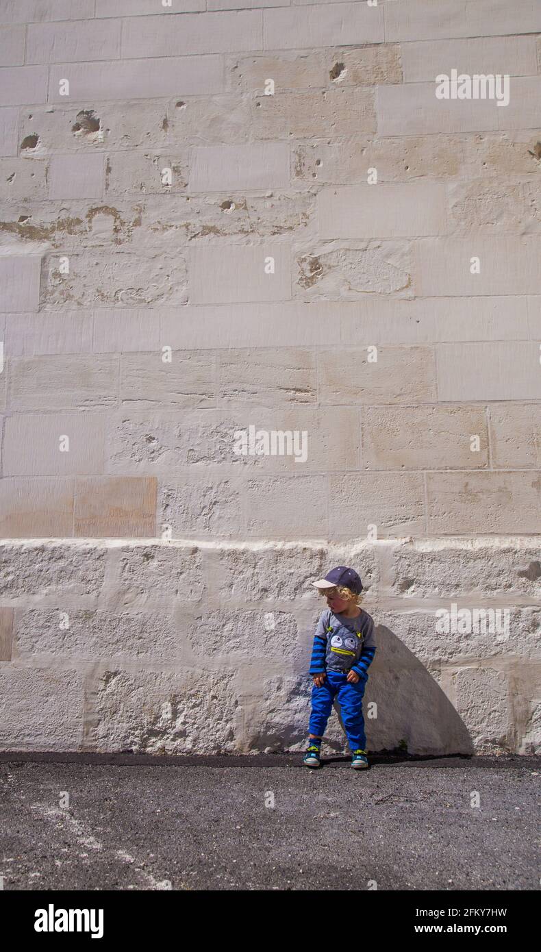 Young Blond hair boy stood against white wall Stock Photo - Alamy