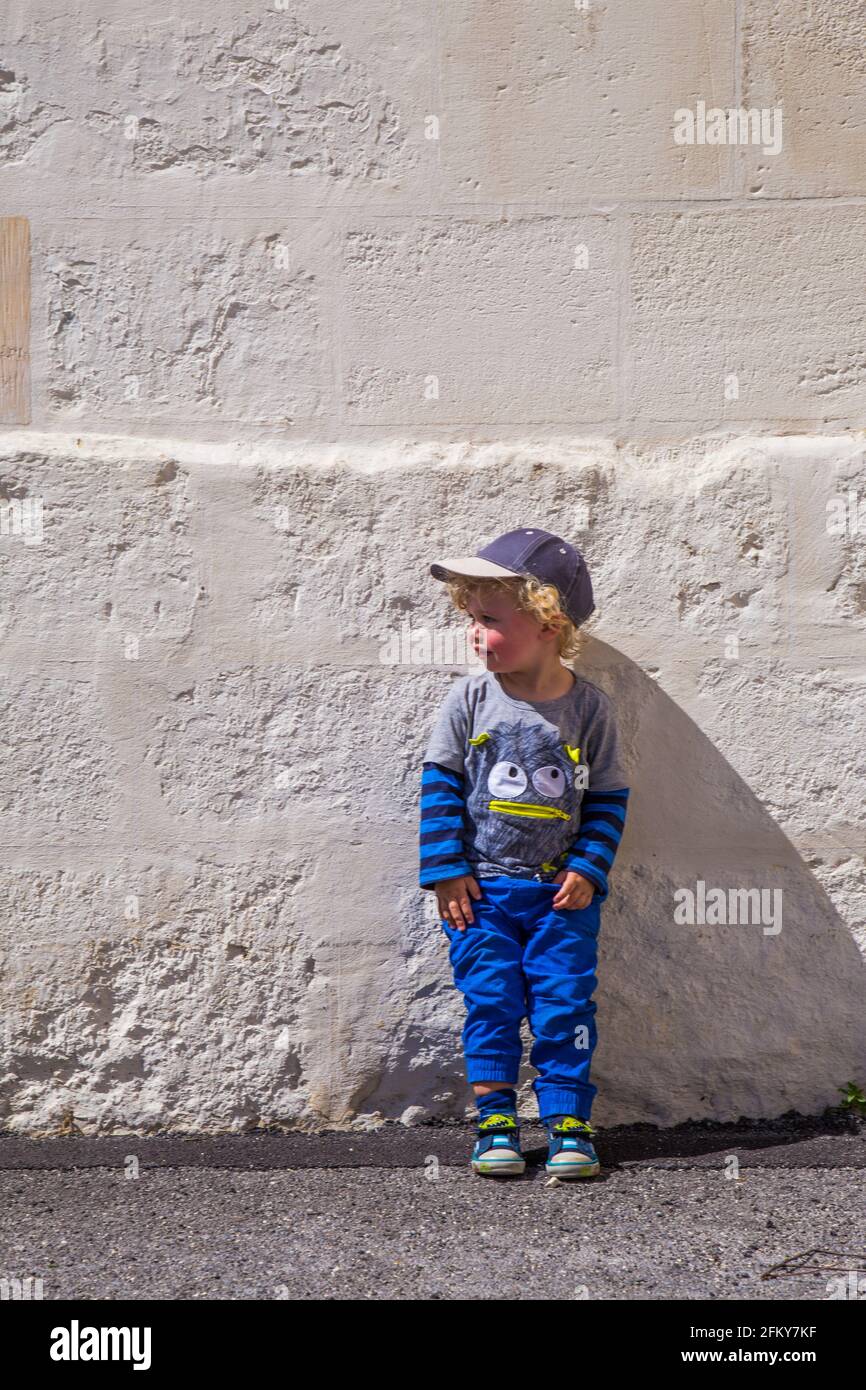 Young Blond hair boy stood against white wall Stock Photo - Alamy