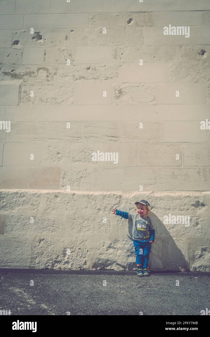 Young Blond hair boy stood against white wall Stock Photo - Alamy