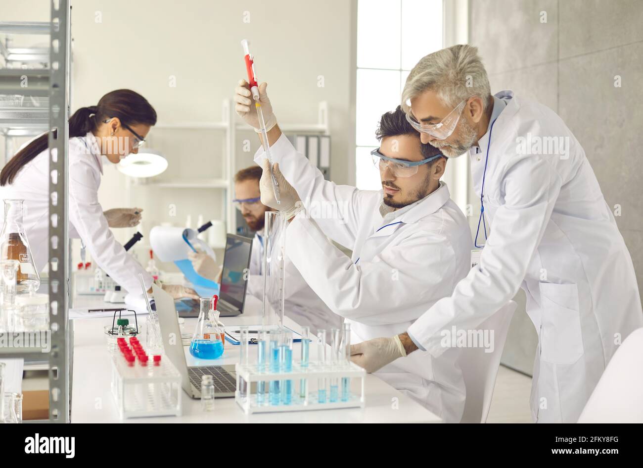 Senior professor and young male scientist discussing test result at ...