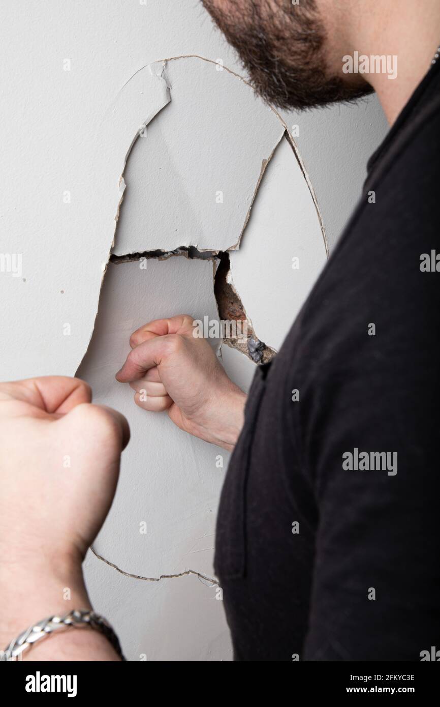 The angry man hits the wall and breaks it Stock Photo - Alamy