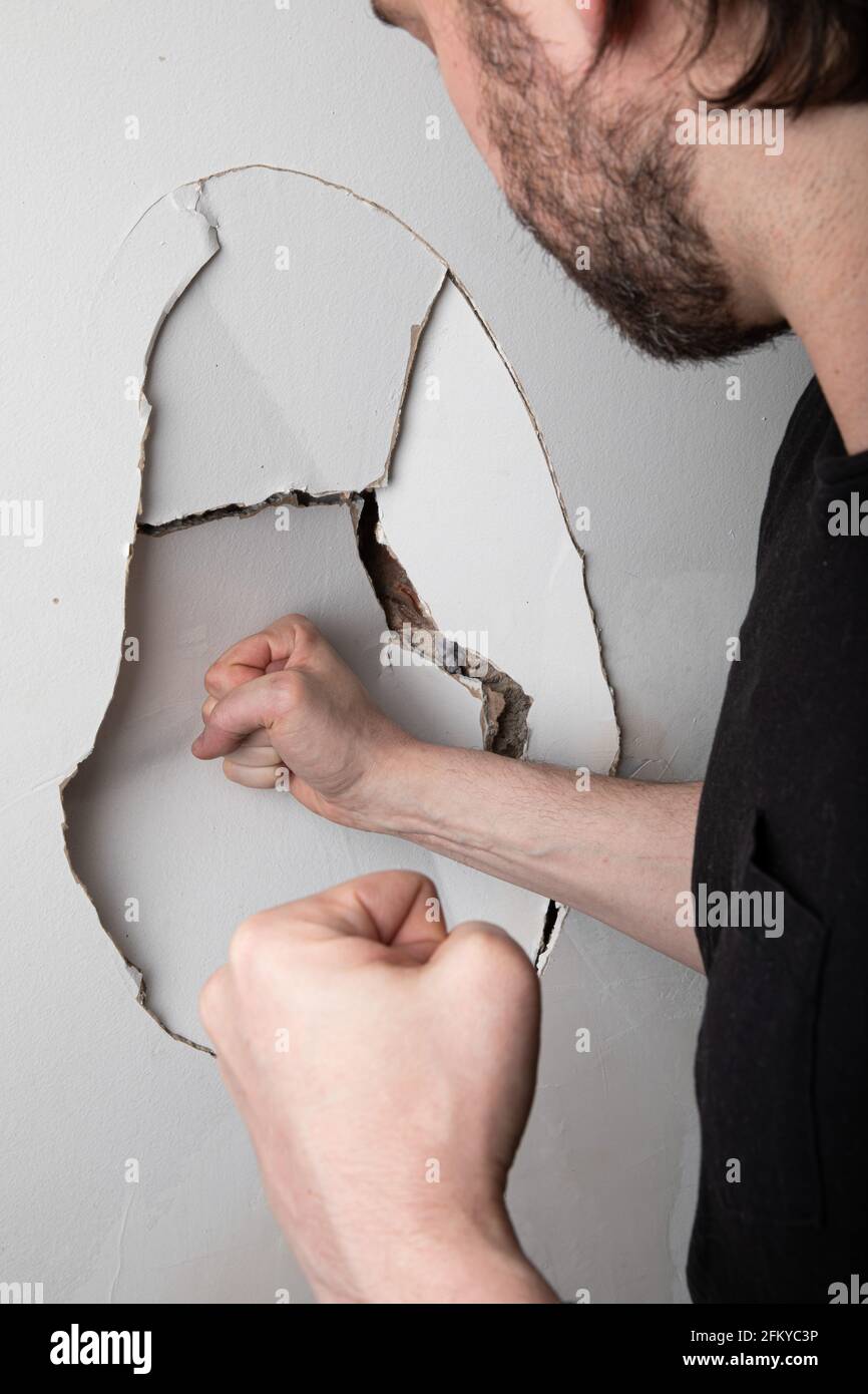 The angry man hits the wall and breaks it Stock Photo - Alamy