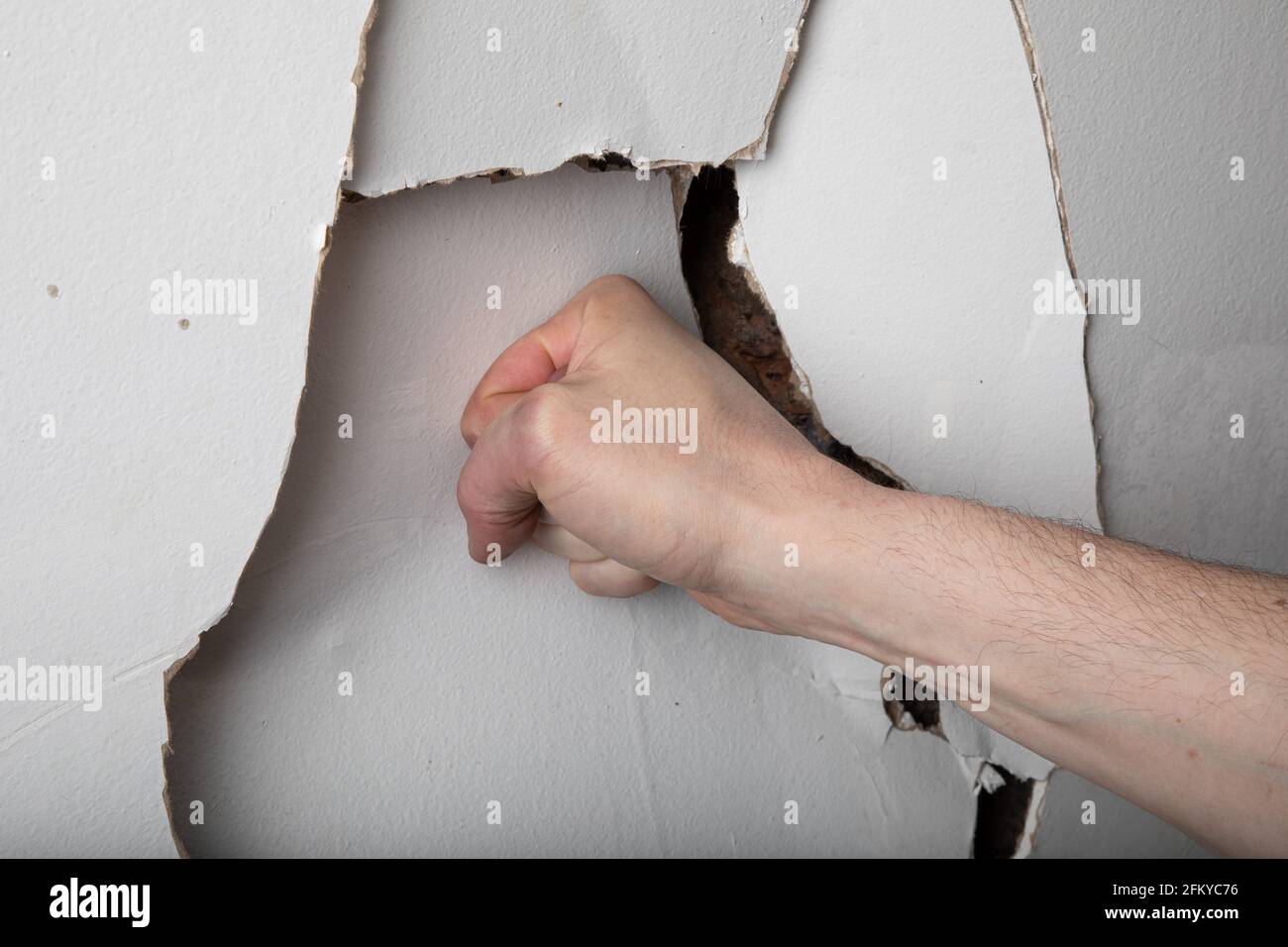 The angry man hits the wall and breaks it Stock Photo - Alamy